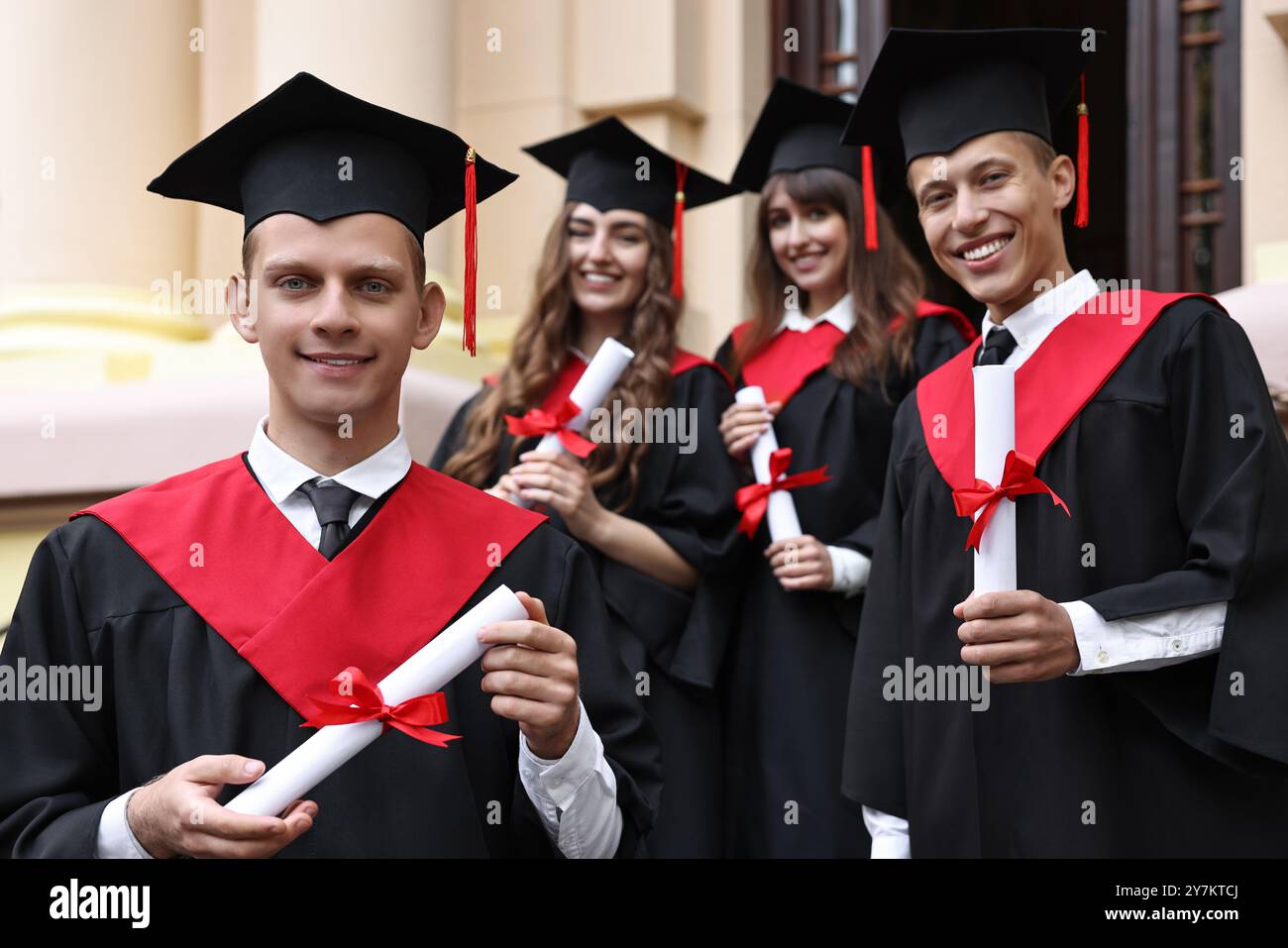 Graduation ceremony. Happy students with diplomas outdoors, selective ...