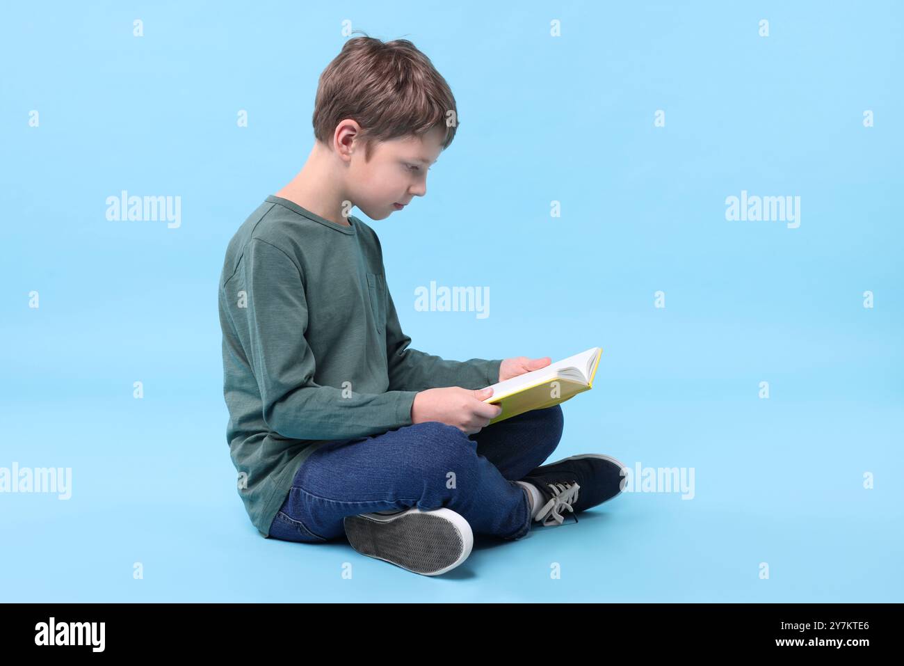 Boy with correct posture reading book on light blue background Stock ...