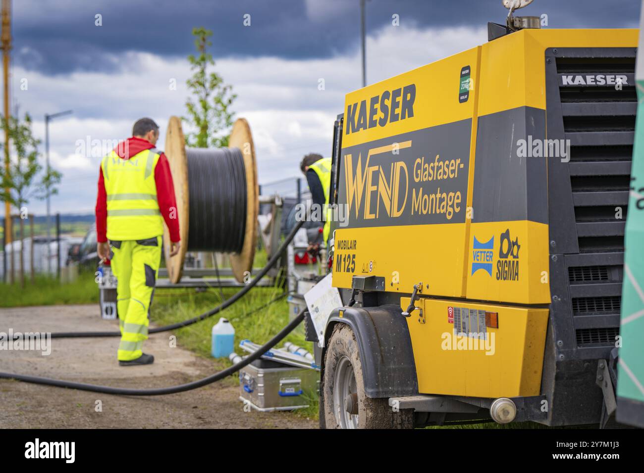 A construction worker works on a construction site with a large cable ...