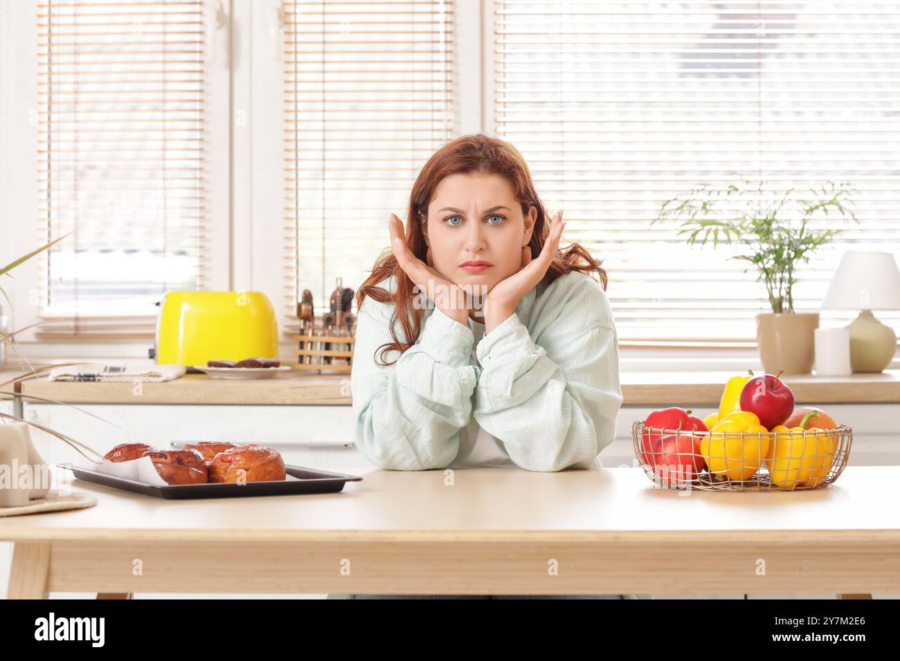 Overweight young woman choosing between healthy and unhealthy food at ...