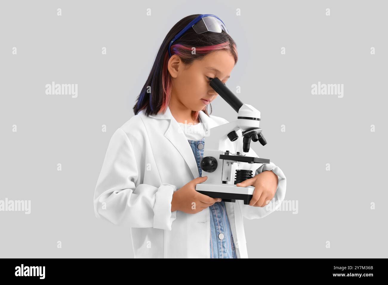 Cute little girl using microscope on grey background Stock Photo - Alamy