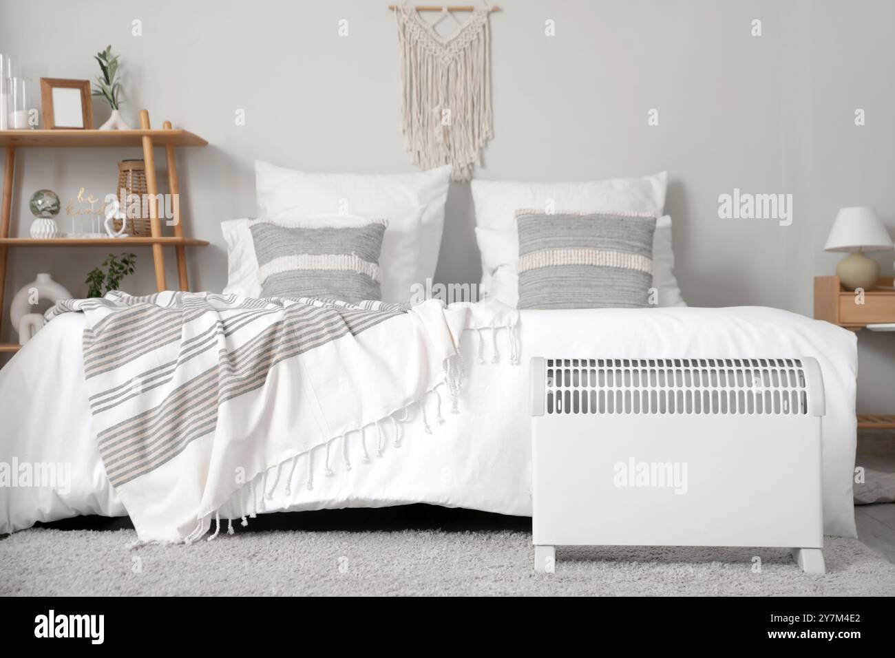 Electric heater on floor near bed in bedroom Stock Photo - Alamy