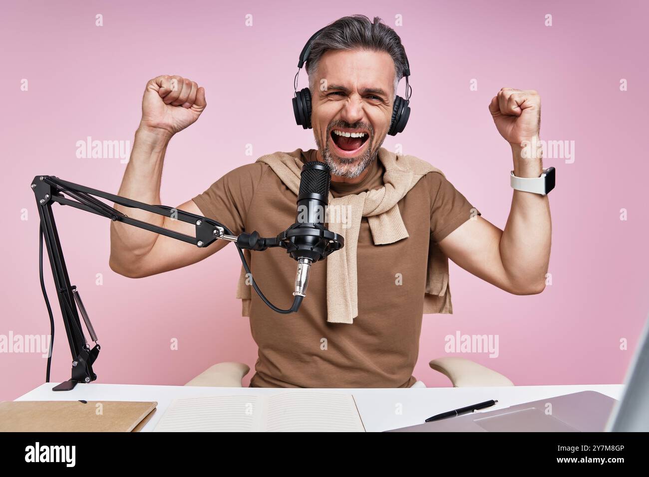 Happy man using microphone and gesturing while recording podcast ...