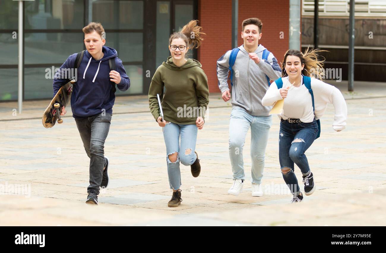 Group of cheerful students running along city street Stock Photo - Alamy