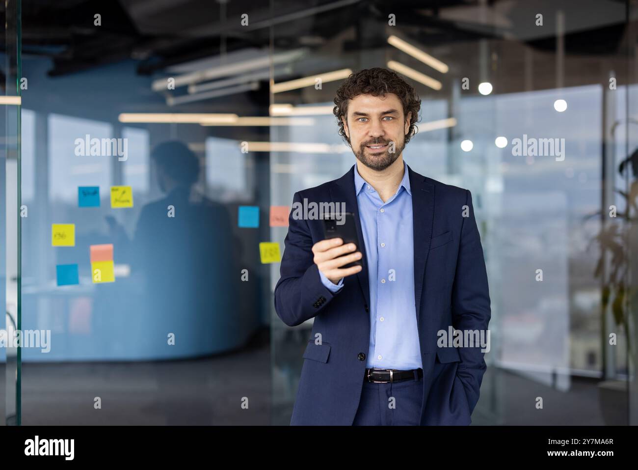 Businessman wearing stylish blue suit holding smartphone in modern ...