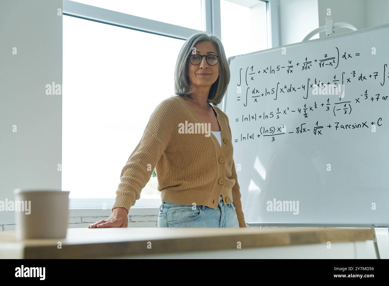 Senior woman teaching mathematics while standing near the whiteboard at ...