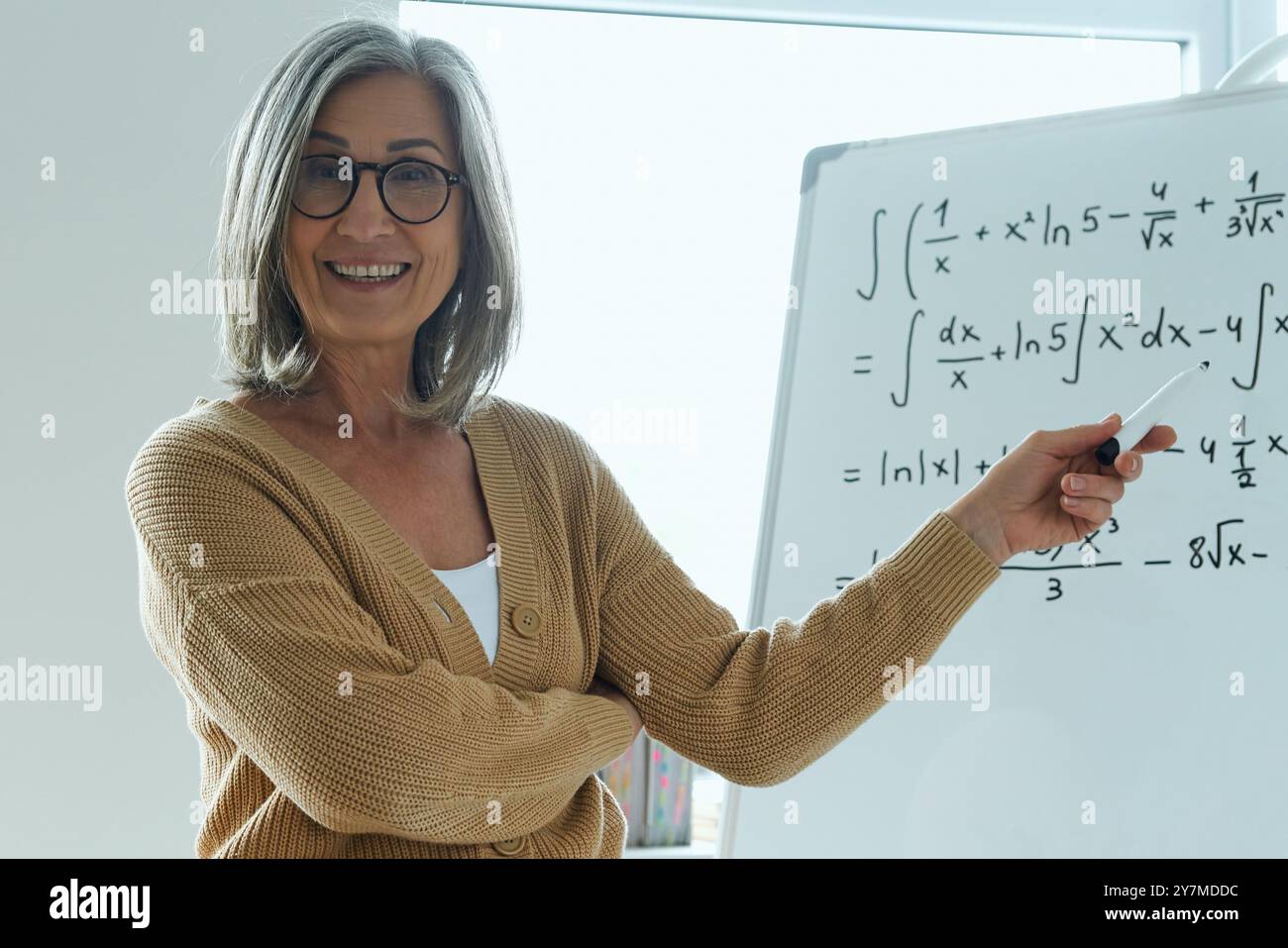 Cheerful senior woman pointing whiteboard while standing at the ...