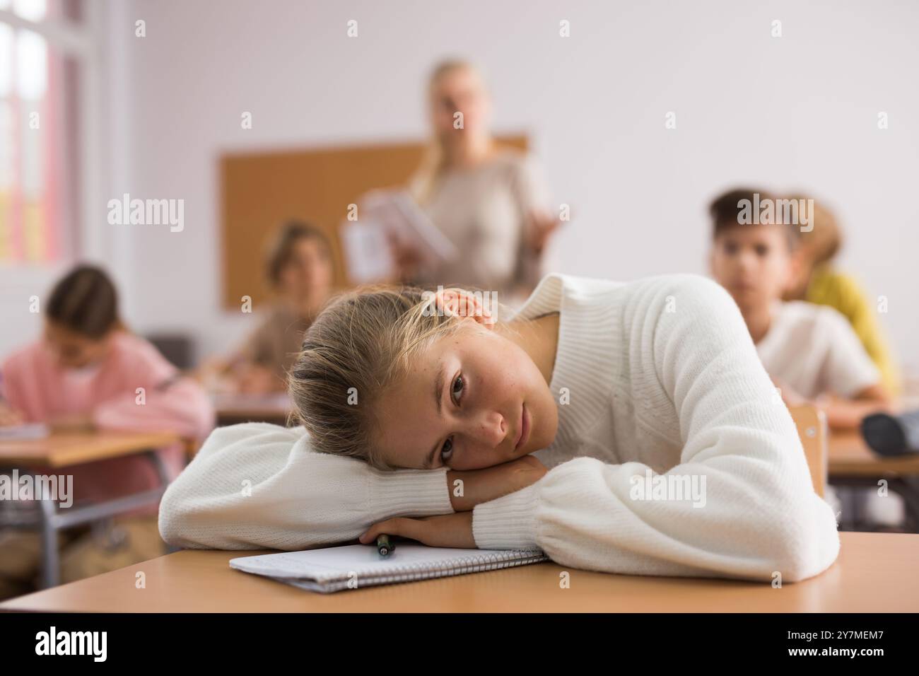 Teenager girl lying on table during lesson Stock Photo - Alamy