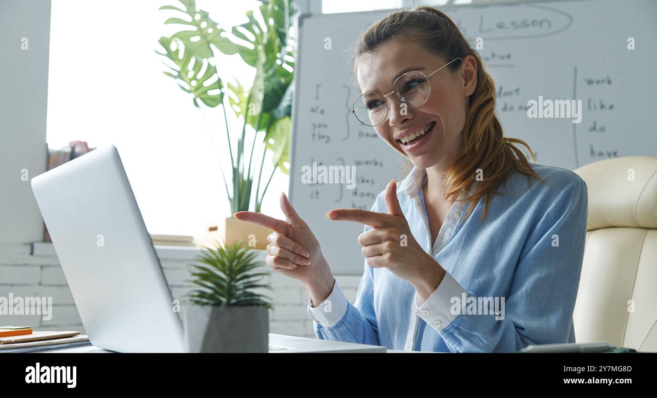 Happy woman using laptop and gesturing while having web conference near ...