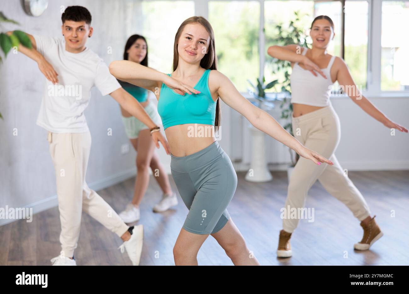 Happy flexible girls and guys exercising active moves with group of ...