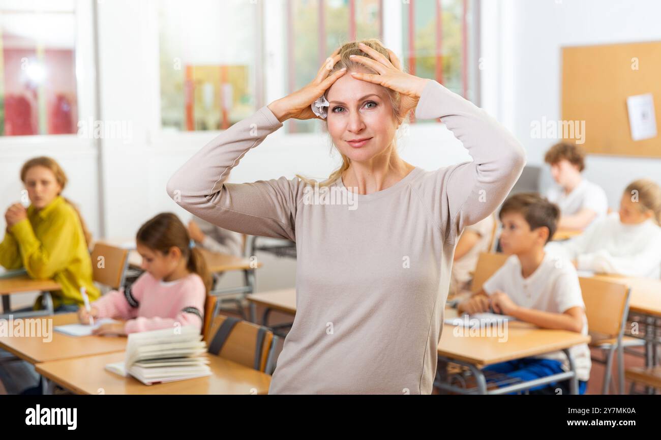 Portrait of teacher holding head in classroom Stock Photo - Alamy
