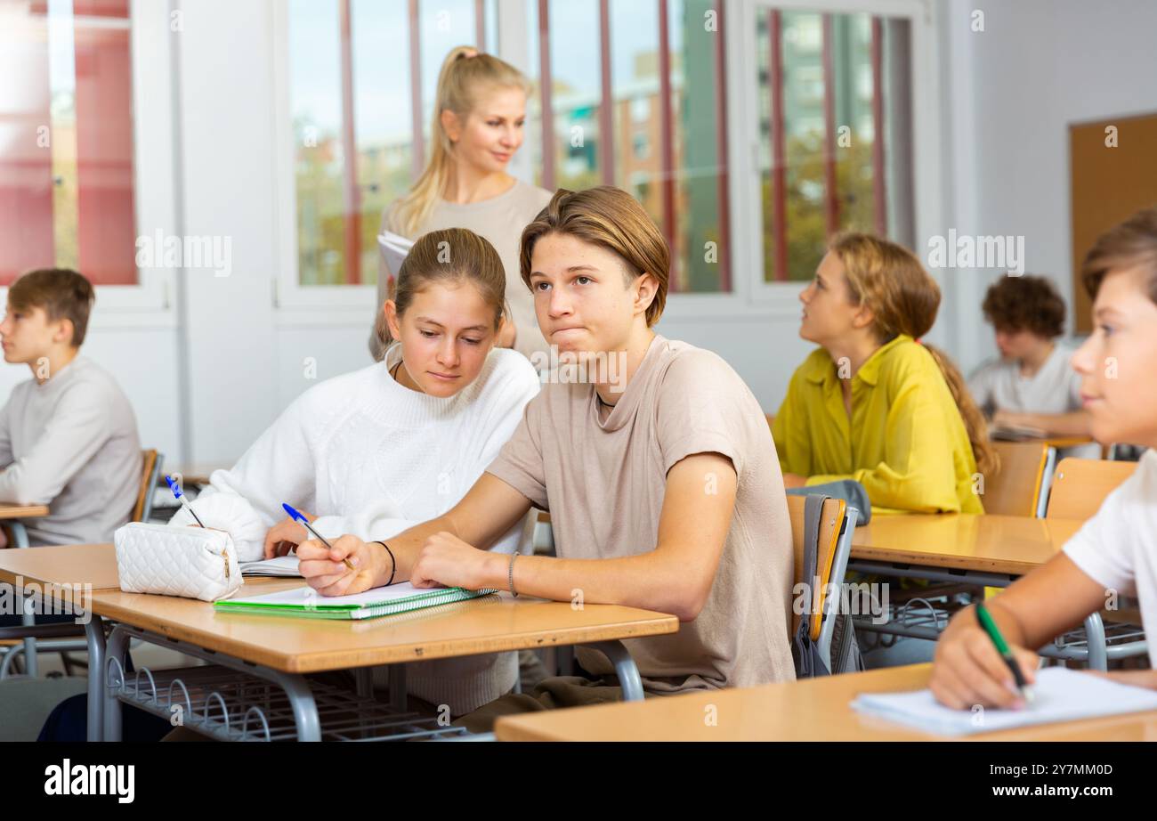 Schoolgirl peeks in a boys notebook during classes in school class ...