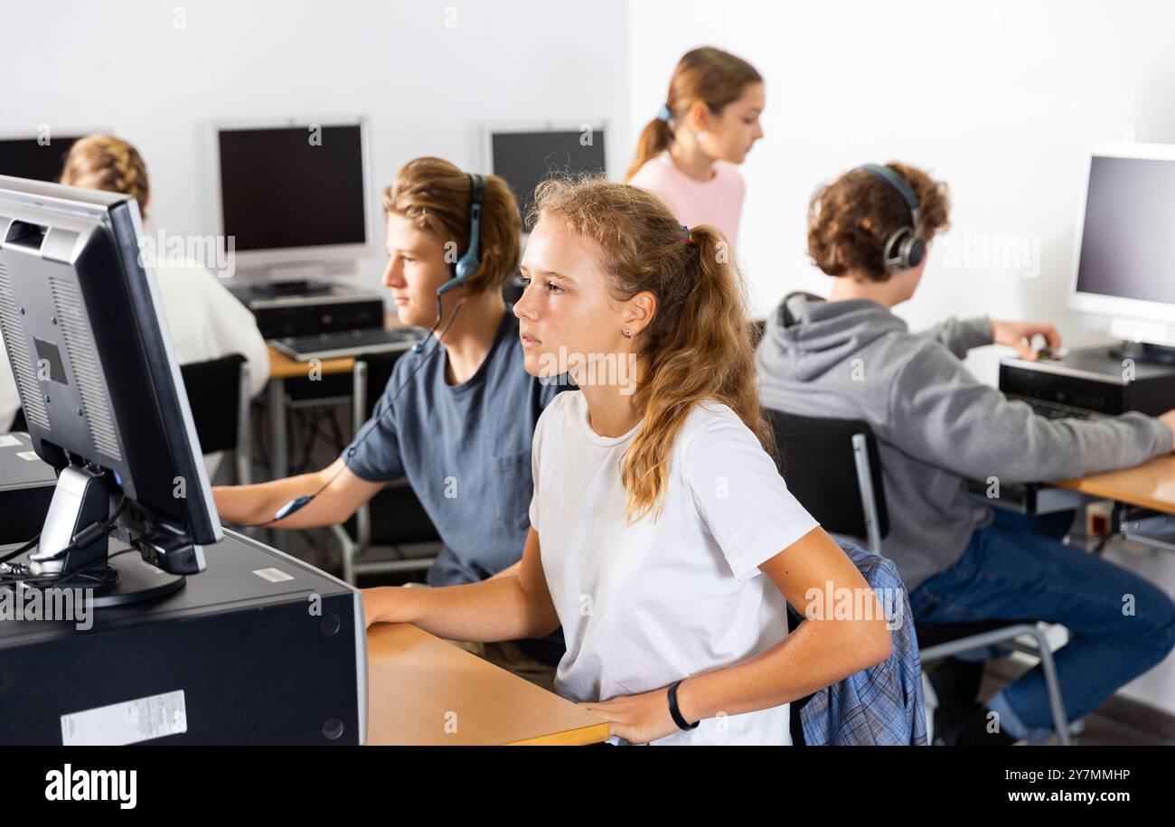 Pupils using computers at lesson, teacher teaching them in class room ...