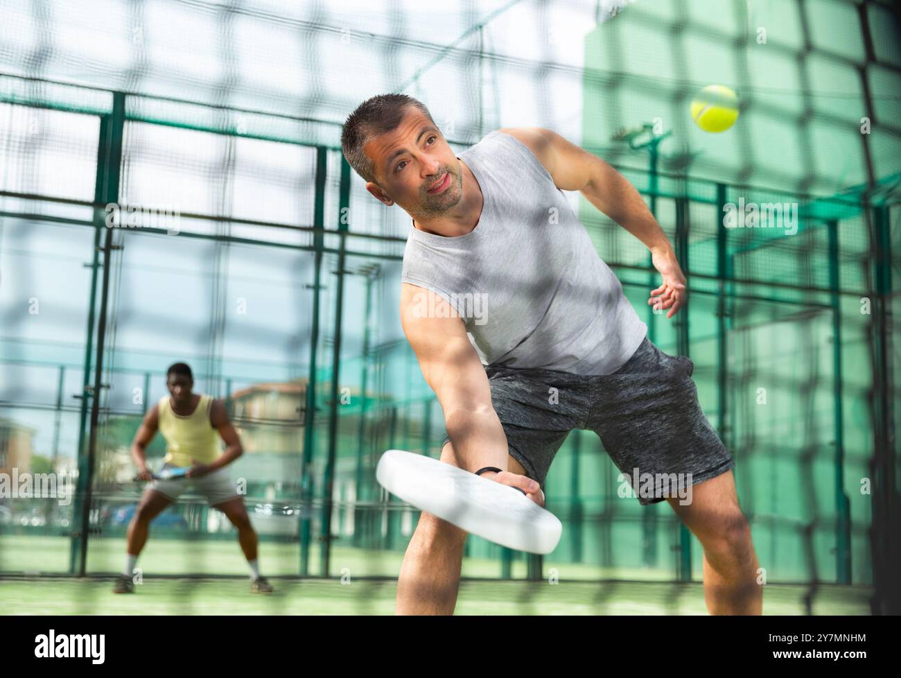 Athletic mens plays padel. View through tennis net Stock Photo - Alamy