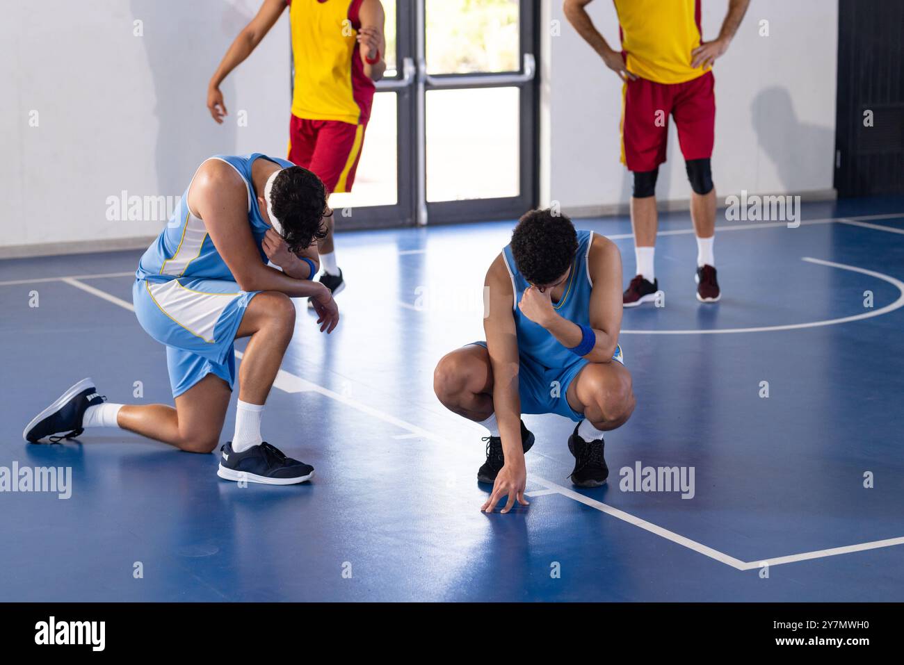 Diverse Basketball players in blue uniforms kneeling on court during ...
