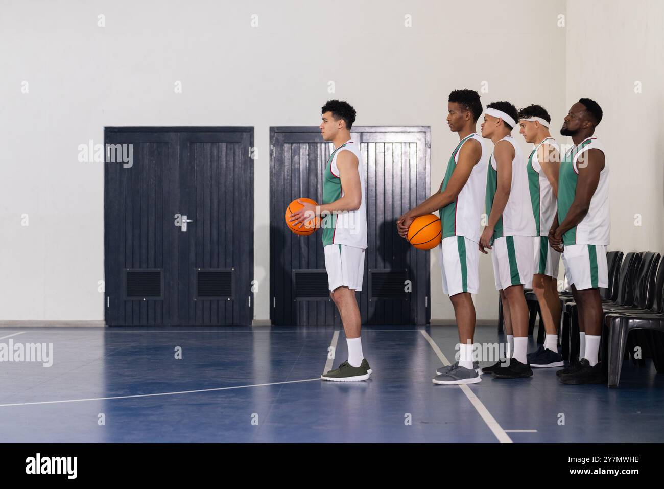 Diverse Basketball players in uniform standing in line holding ...