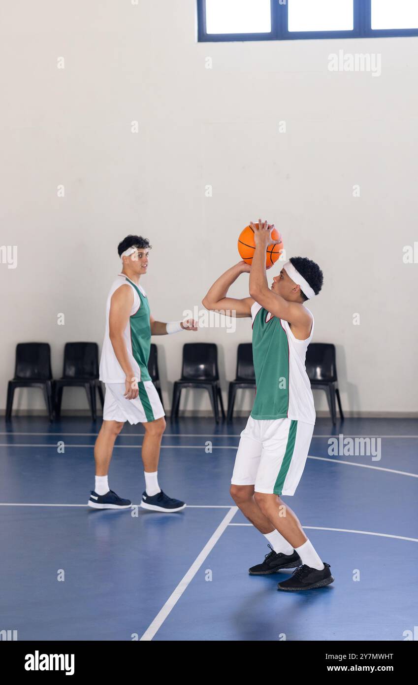 Playing basketball, two players in uniform practicing on indoor court ...