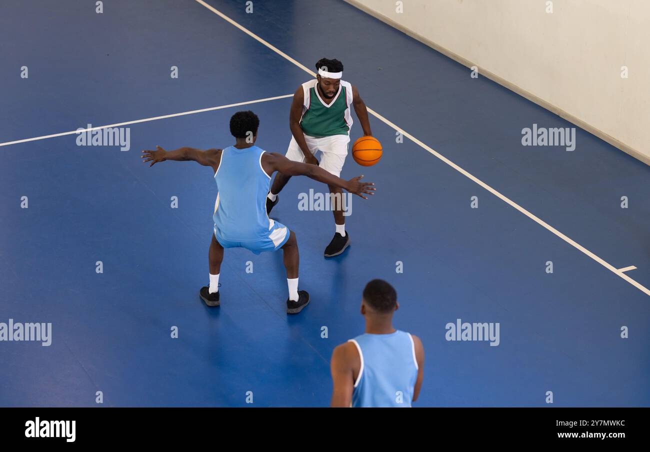 Playing basketball, athlete dribbling ball while being defended on ...