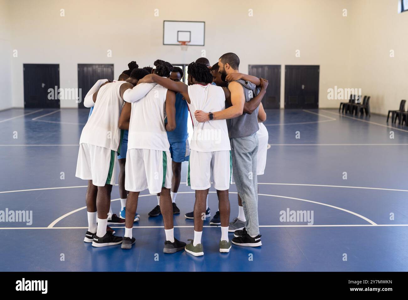 Huddling together, basketball team preparing for game in indoor court ...