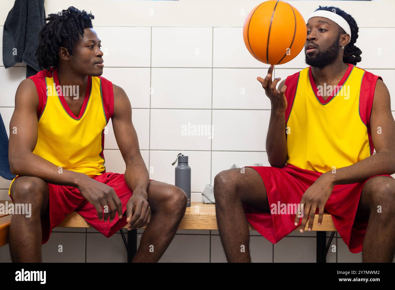 In locker room, African American basketball players sitting on bench ...