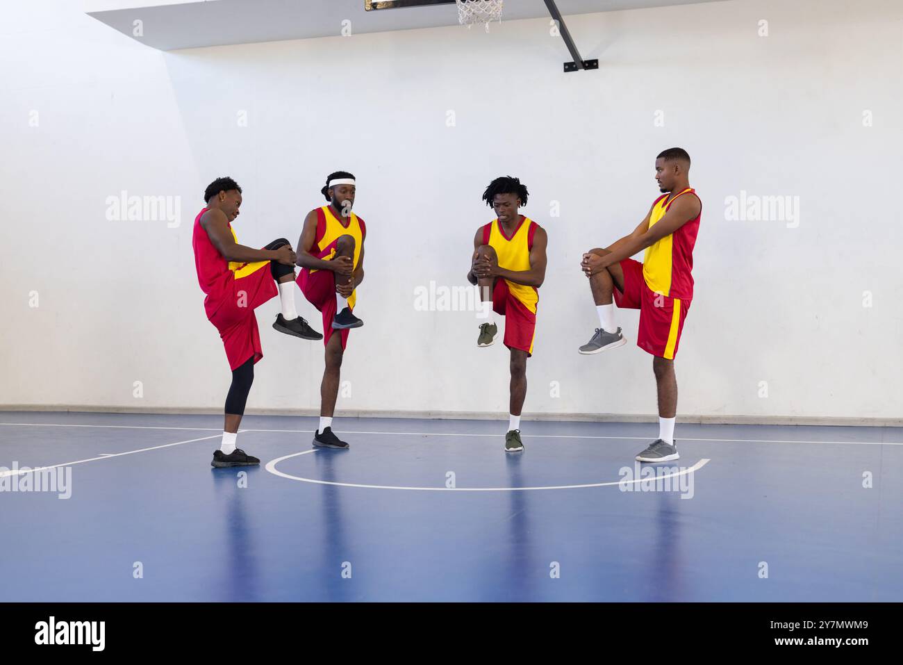 African American basketball players in gym stretching legs before game ...