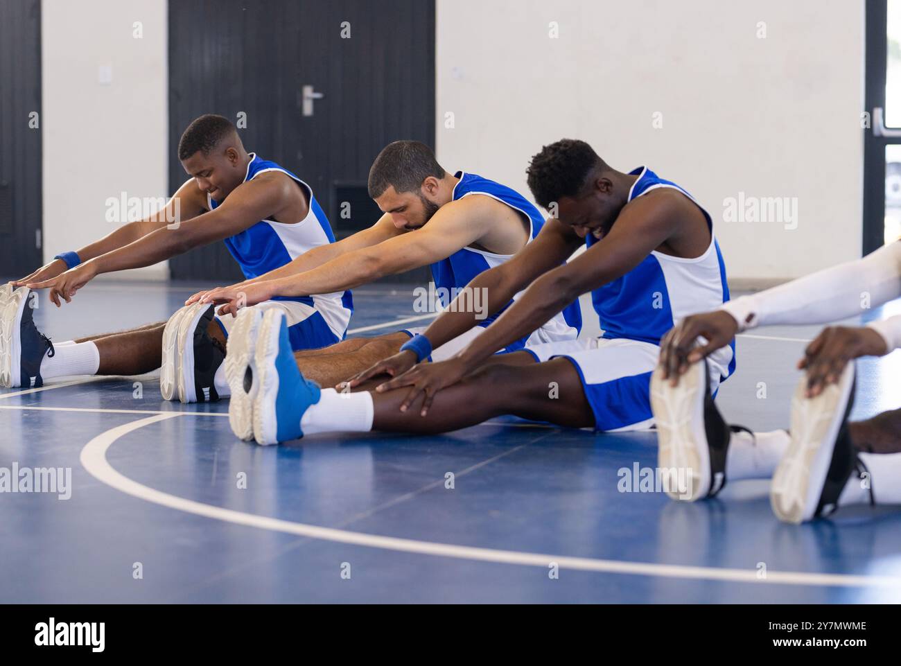 African American basketball players stretching on court, preparing for ...