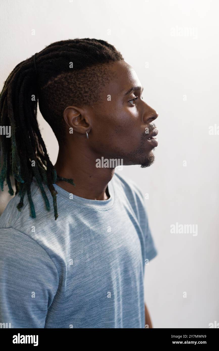 Looking thoughtful, man with dreadlocks wearing blue shirt in profile ...