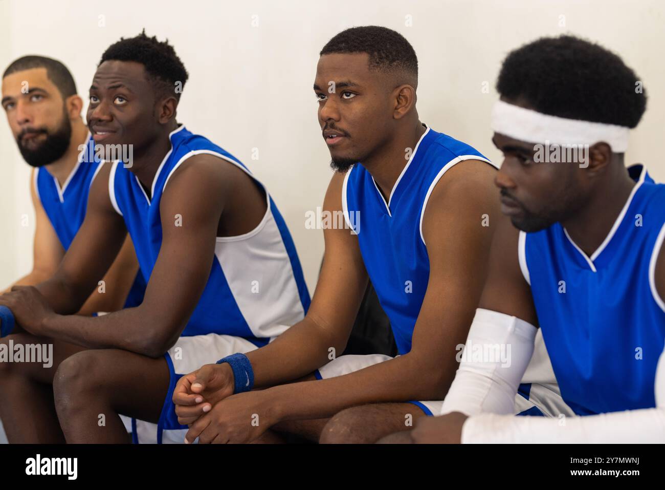 African American basketball players sitting on bench in gym, wearing ...