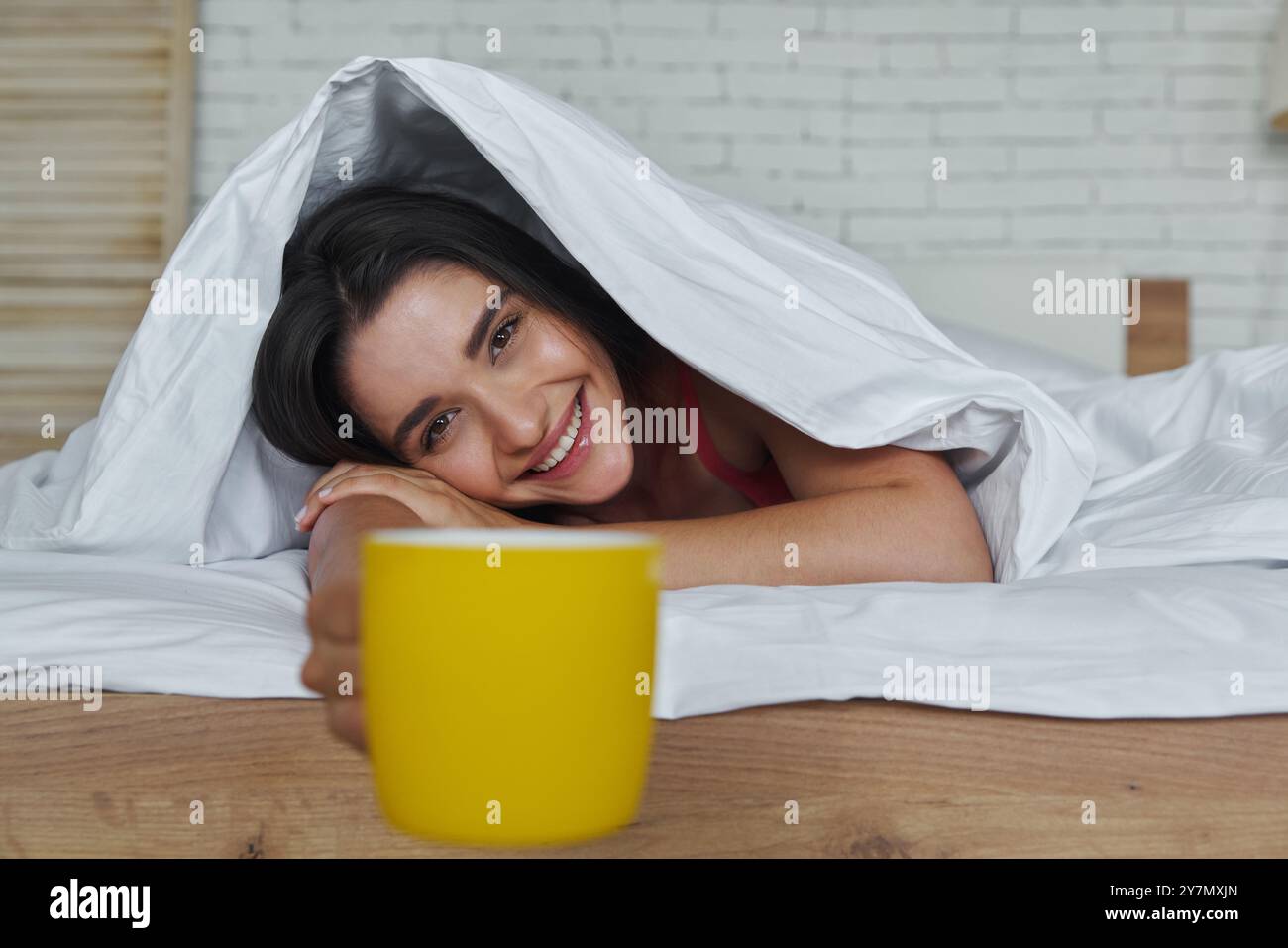 Beautiful woman looking out of a blanket and stretching out hand with ...
