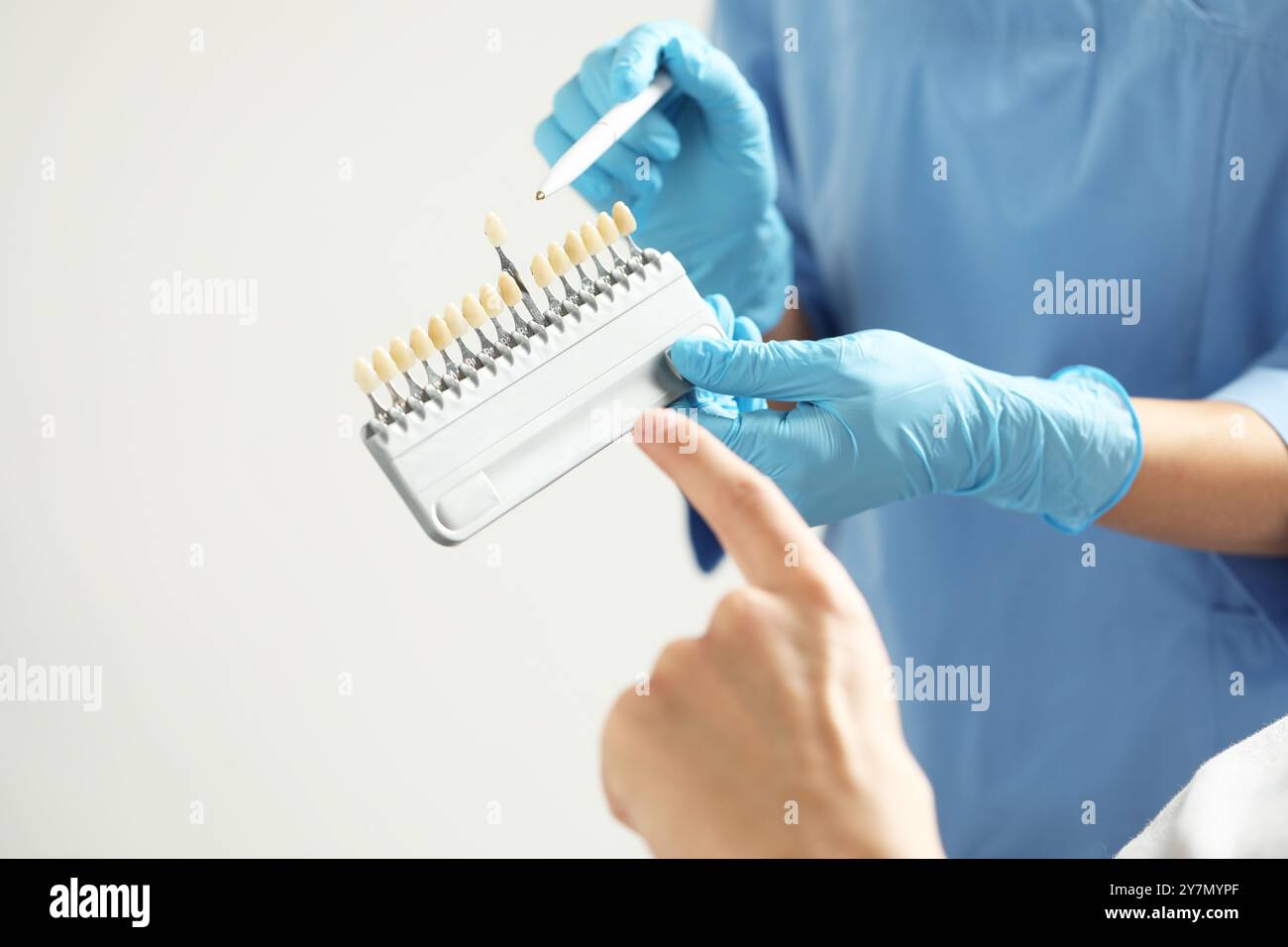 Doctor and patient choosing shade on teeth color palette in clinic ...