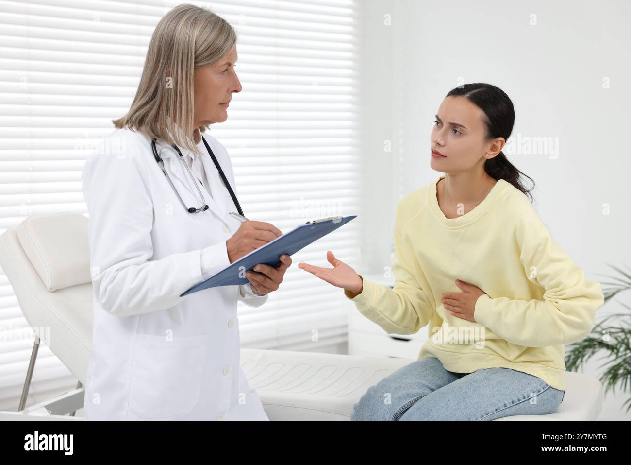 Senior doctor consulting patient with stomach pain in hospital Stock ...