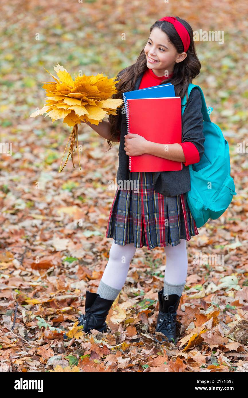 Autumn girl in uniform hold fall leaves outdoor. Stylish teen girl at ...
