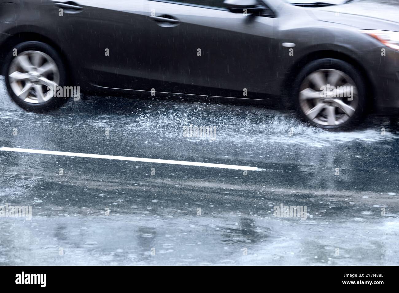 car crossing a flooded road after strong rain. car traffic in rainy ...