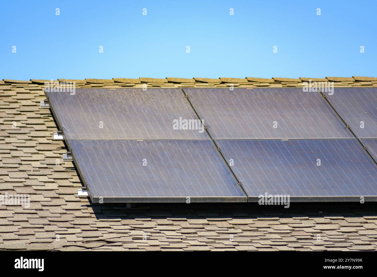 Dirty solar panels mounted on a residential roof with asphalt shingles ...