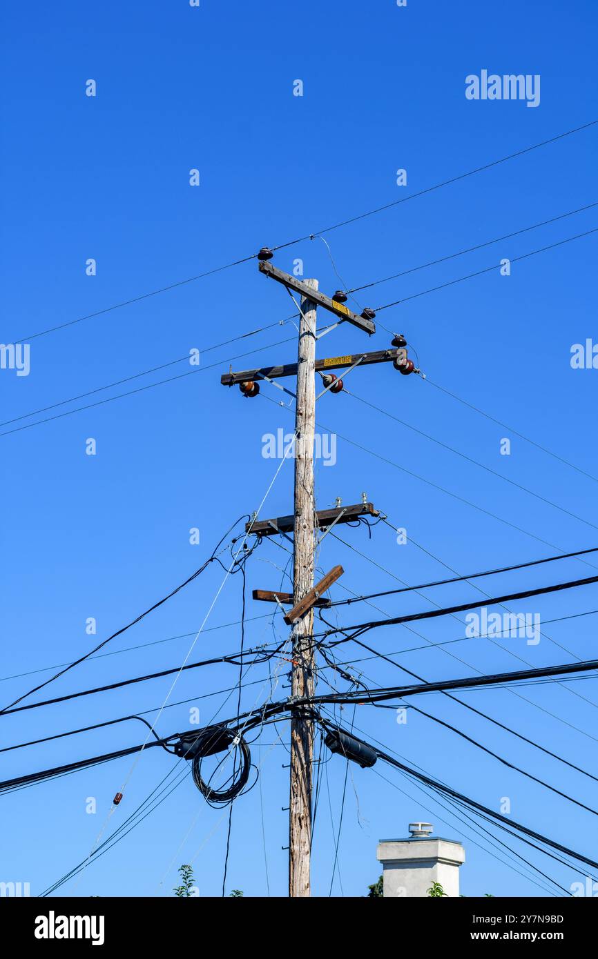 A tall wooden utility pole with multiple wires and cables running in ...