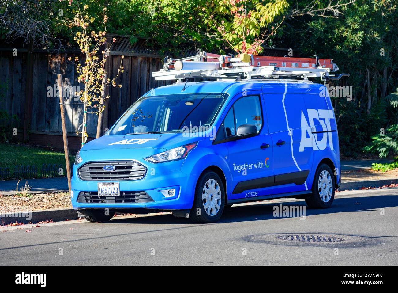 Blue ADT service van is parked on a residential street. The vehicle is ...