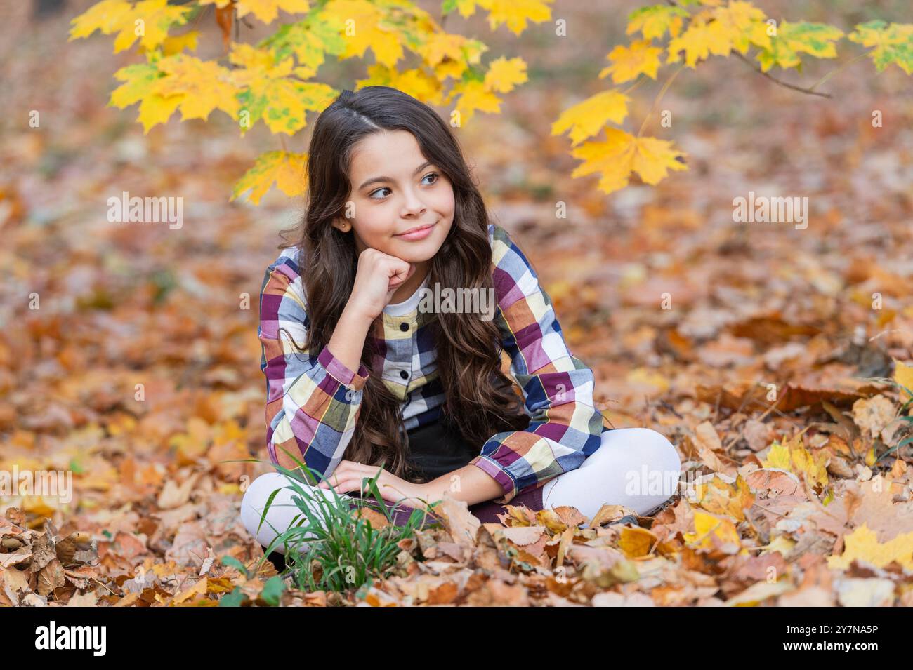 Autumn girl in school uniform sit in fall leaves outdoor. Stylish teen ...