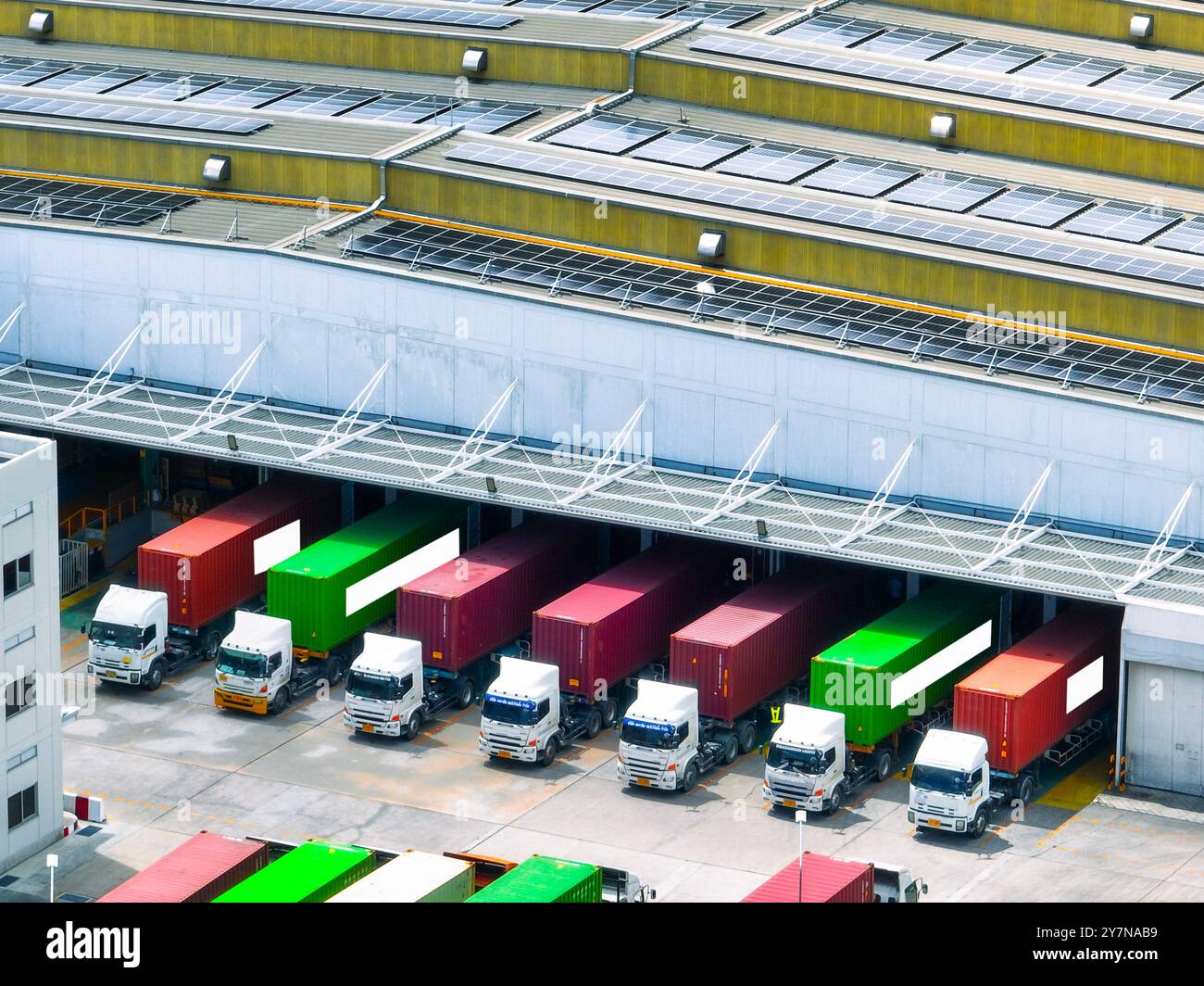 Solar-powered warehouse facility with freight trucks at loading docks ...