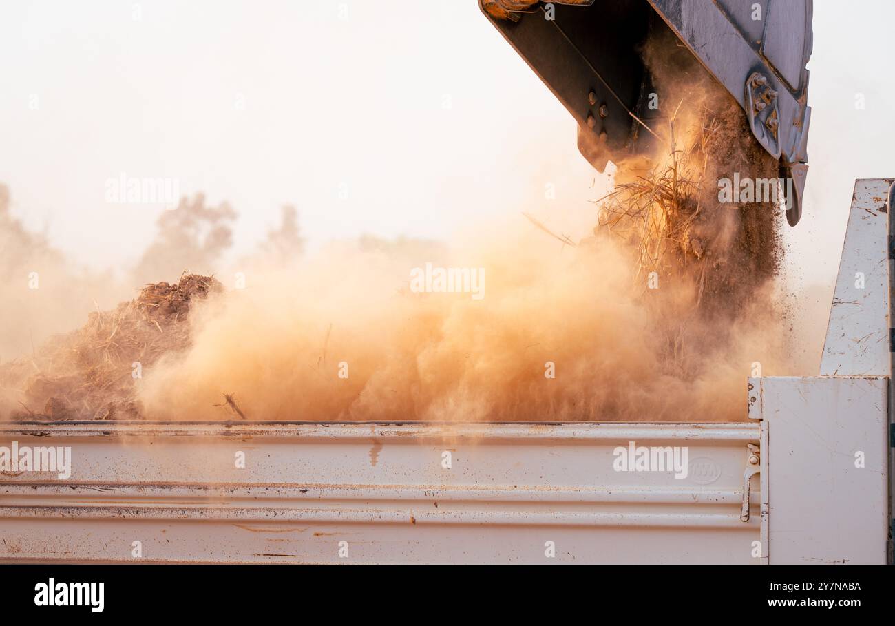 Backhoe loading soil into heavy duty dump truck at construction site ...