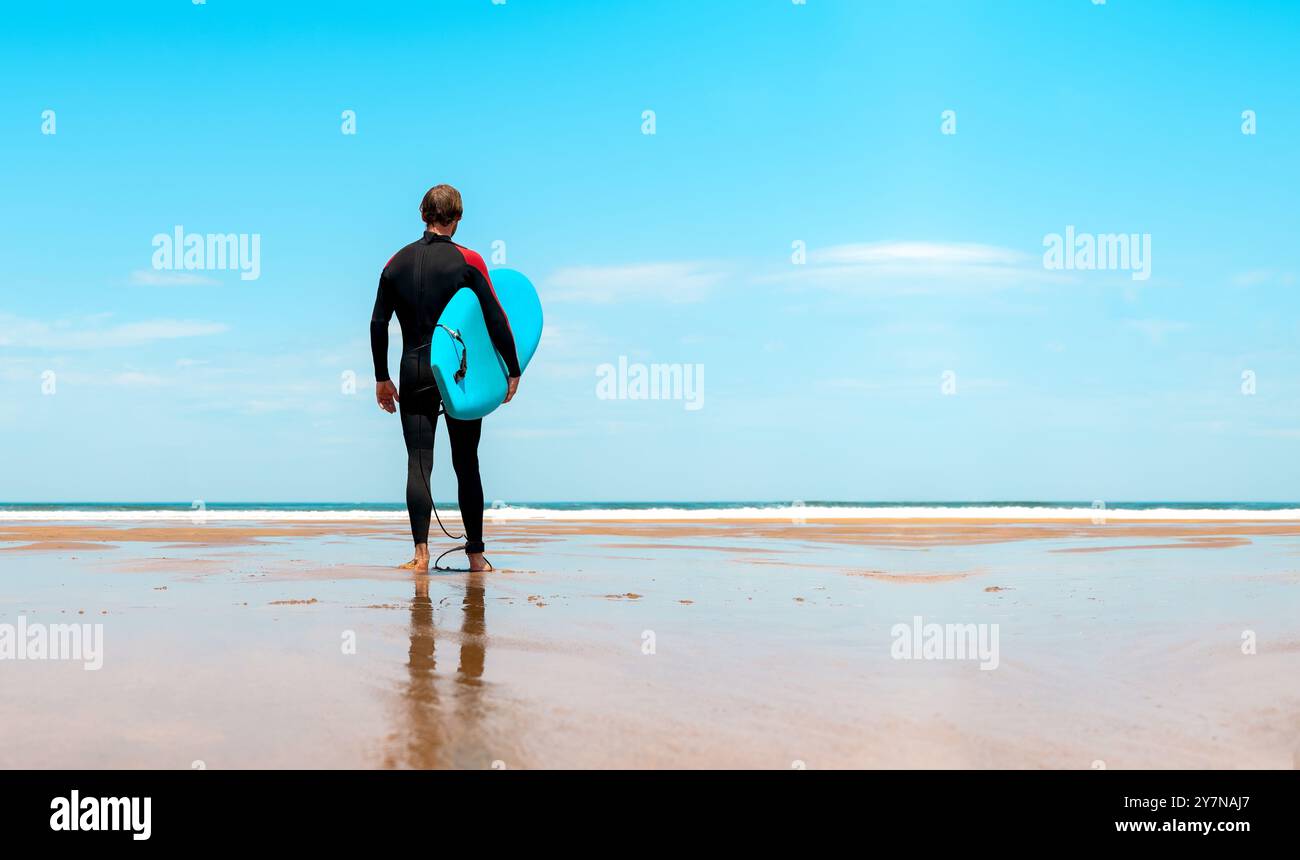 Back view of a surfer man with surfboard standing on the beach Stock ...
