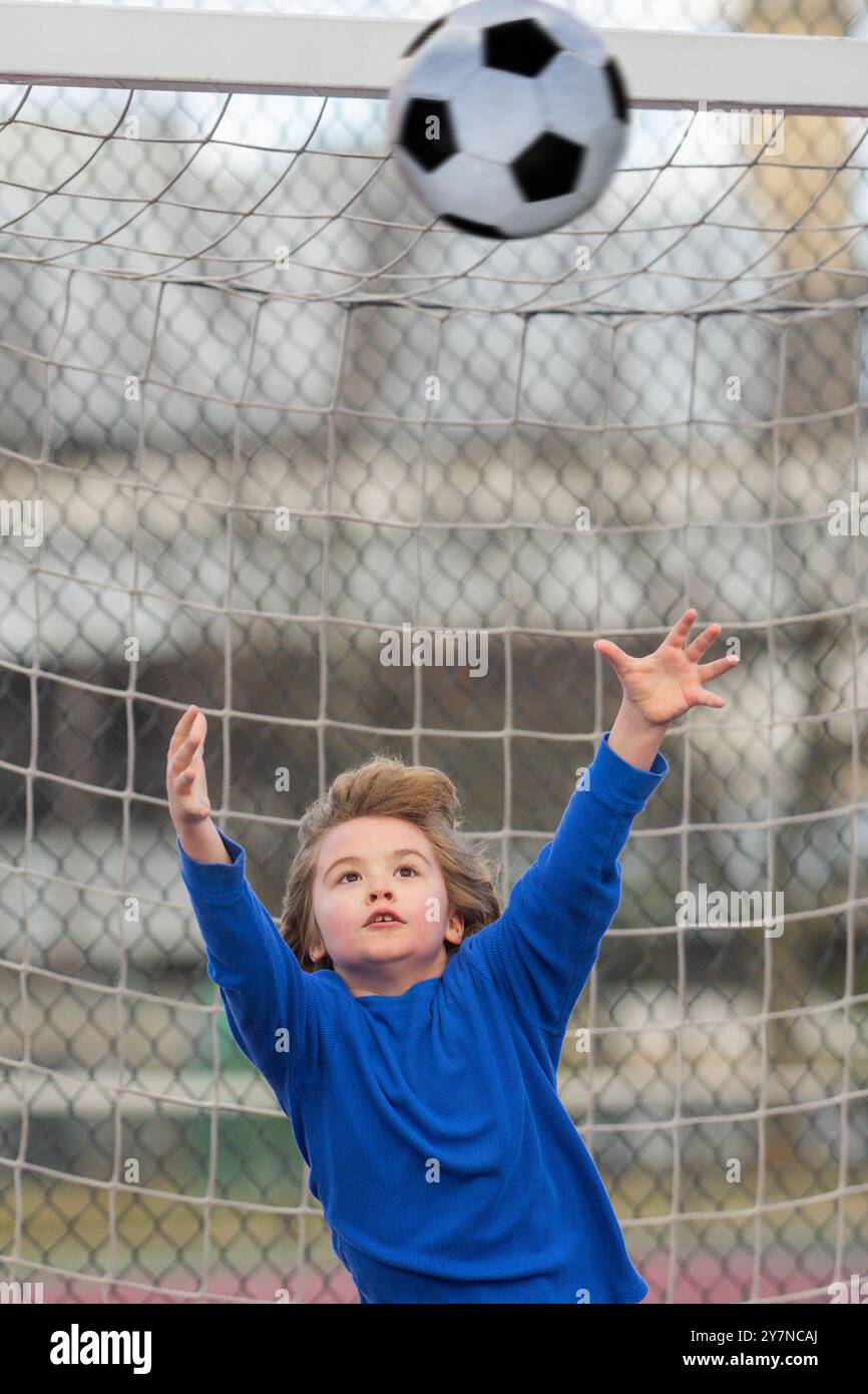 Kid Goalkeeper catches the ball in stadium during a football game ...