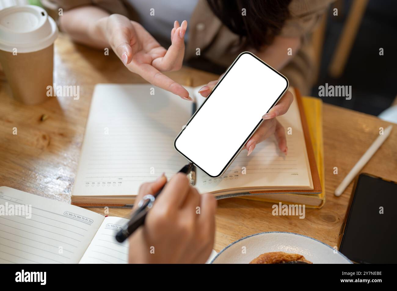 A close-up of a woman showing her smartphone to a friend while ...