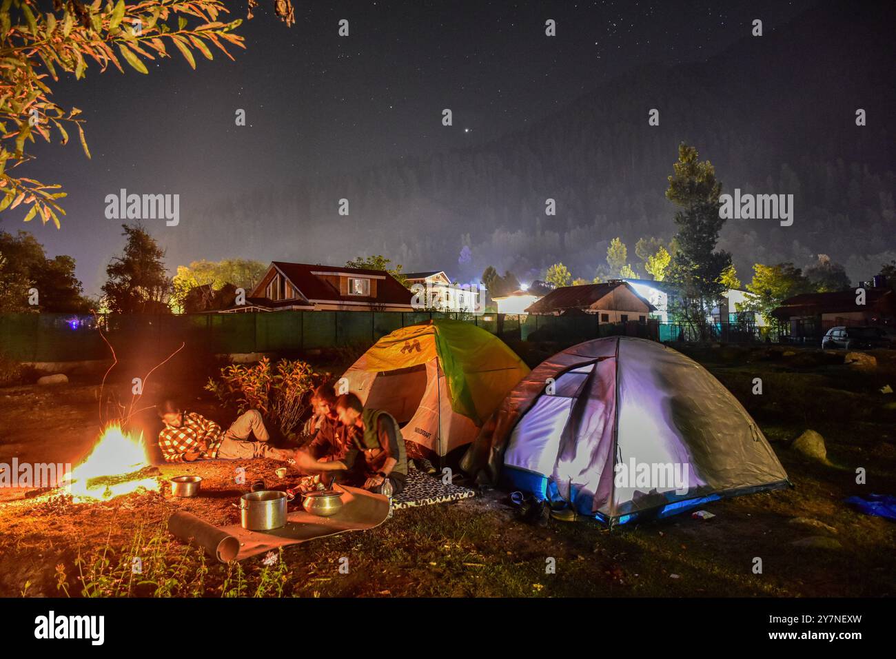 Pahalgam, India. 30th Sep, 2024. Visitors gather around a bonfire under ...