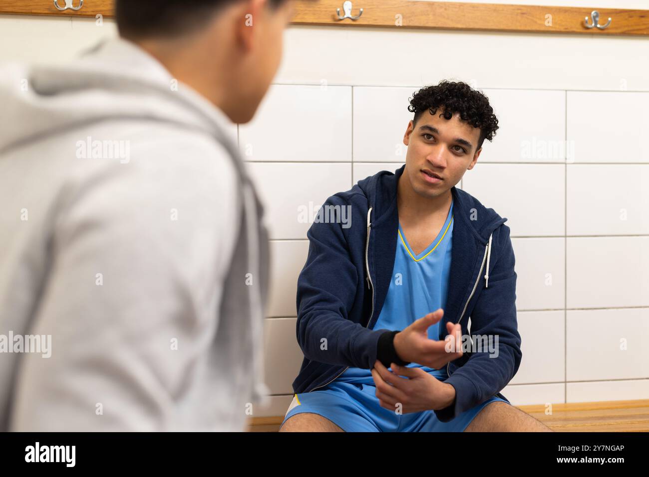 Talking with teammate, basketball player in locker room before game ...