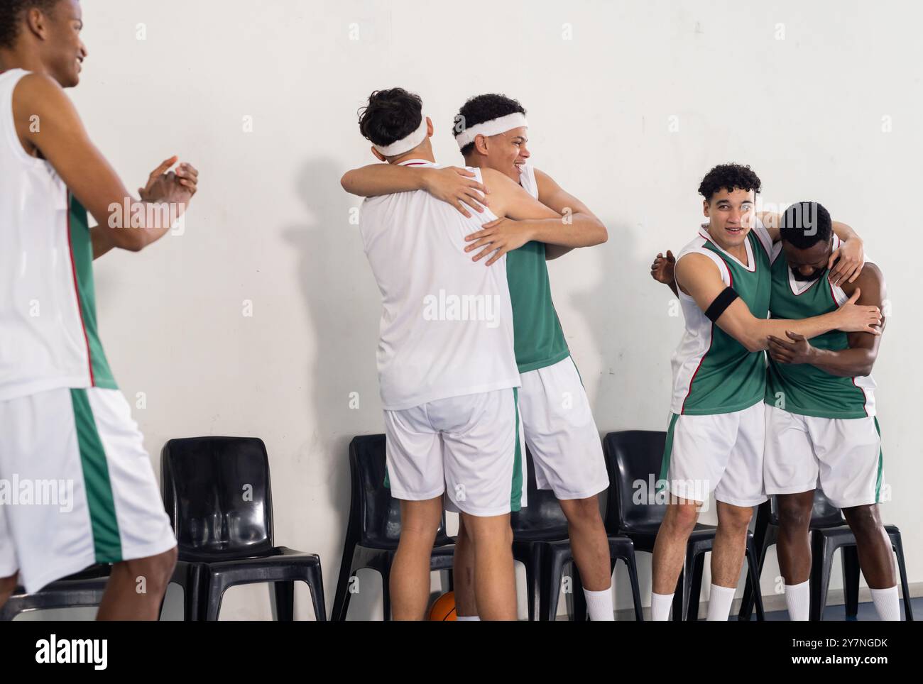 Celebrating victory, basketball team hugging and cheering on court ...