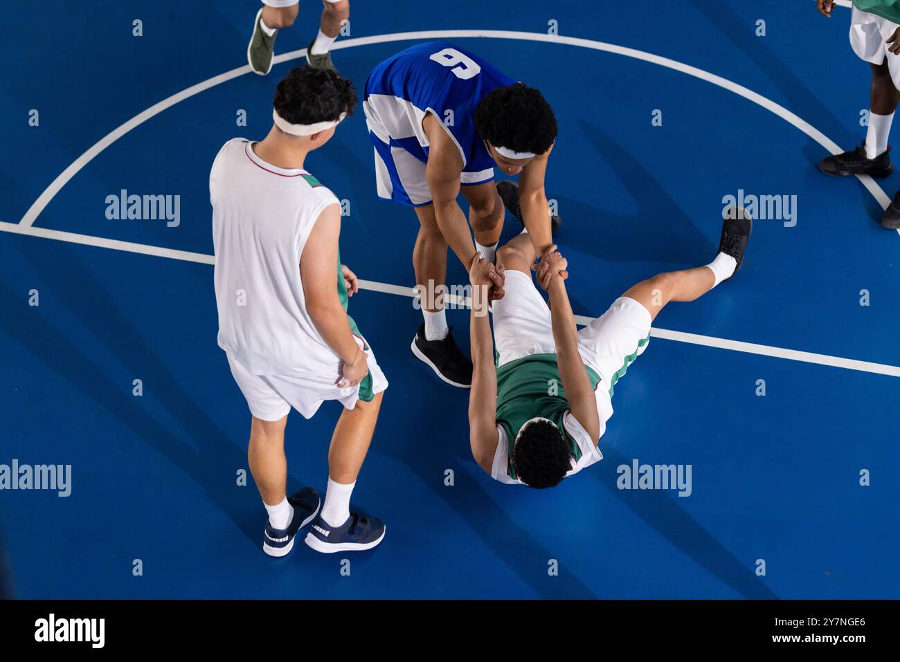 Helping teammate up, basketball players on court during game, showing ...