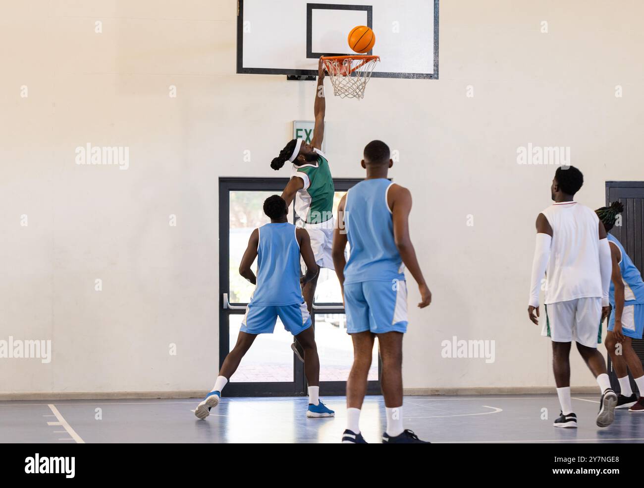 Playing basketball, athlete dunking ball while teammates watch in ...
