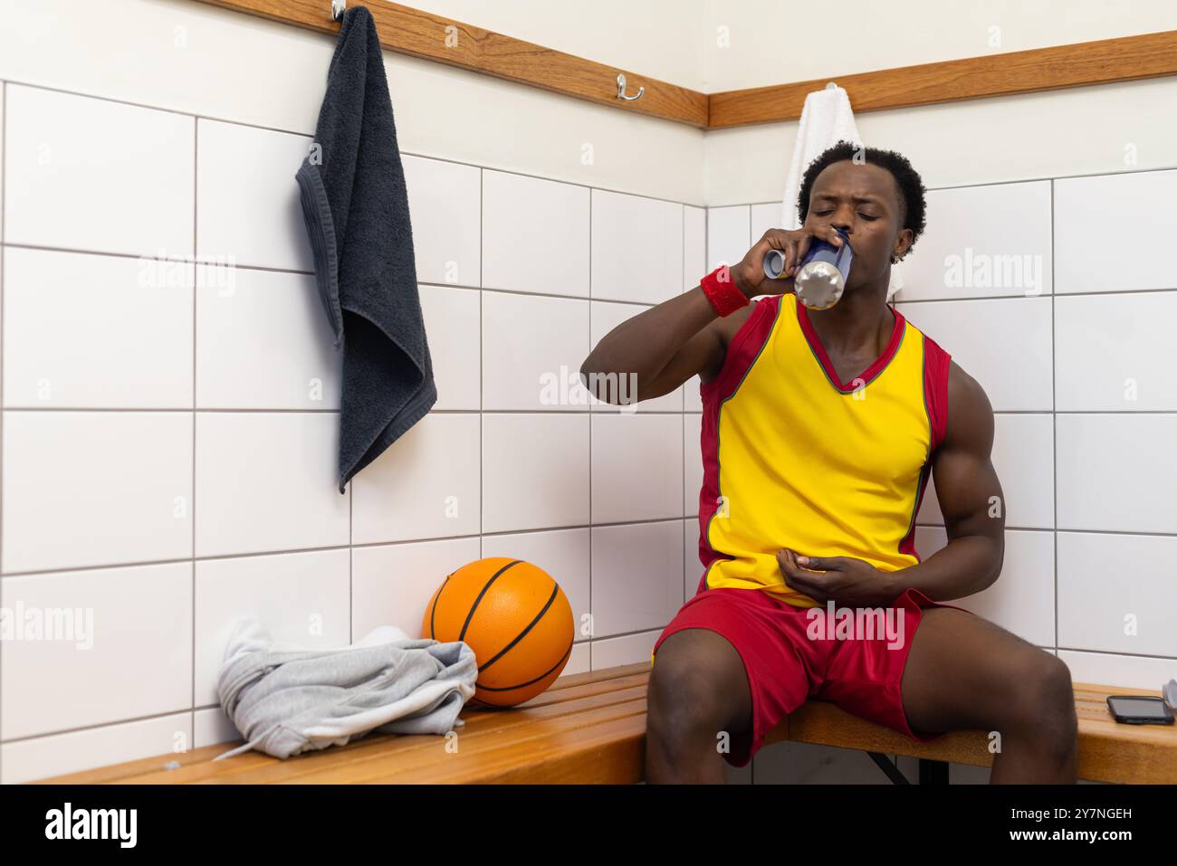 Drinking from can, basketball player in locker room sitting on bench ...