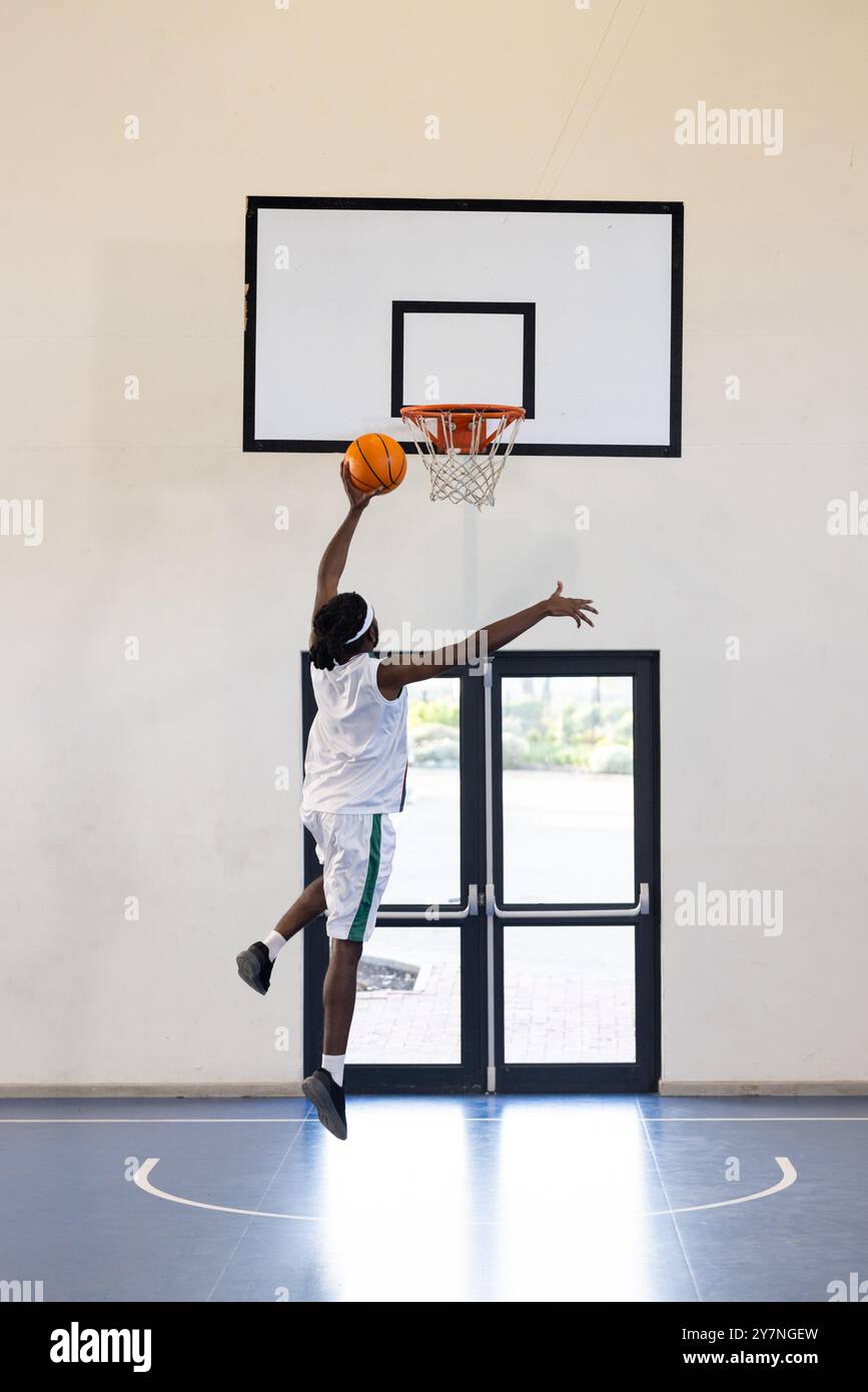 Playing basketball, athlete jumping and dunking ball in indoor court ...