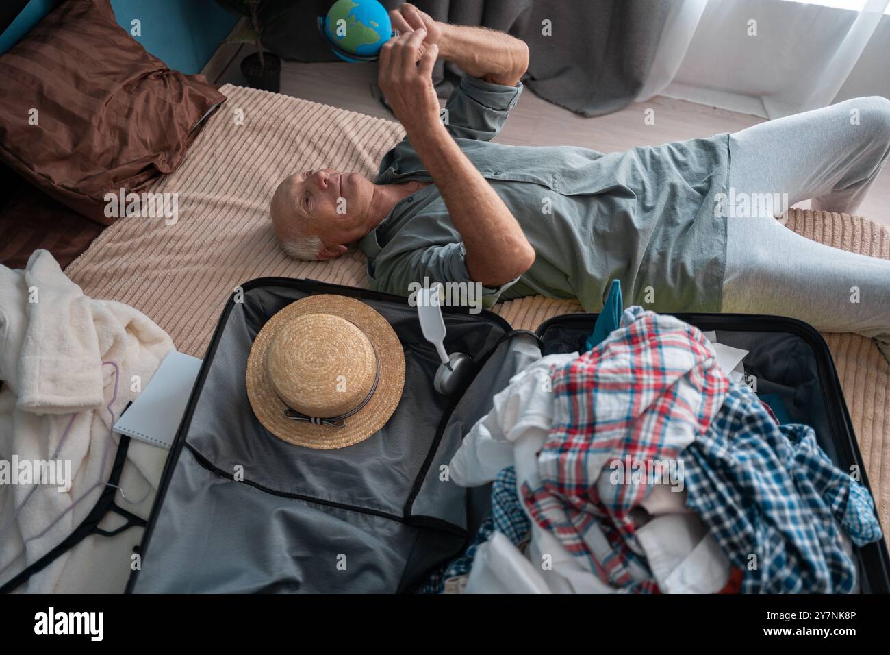 Elderly man packing his travel essentials on suitcase, getting ready to ...